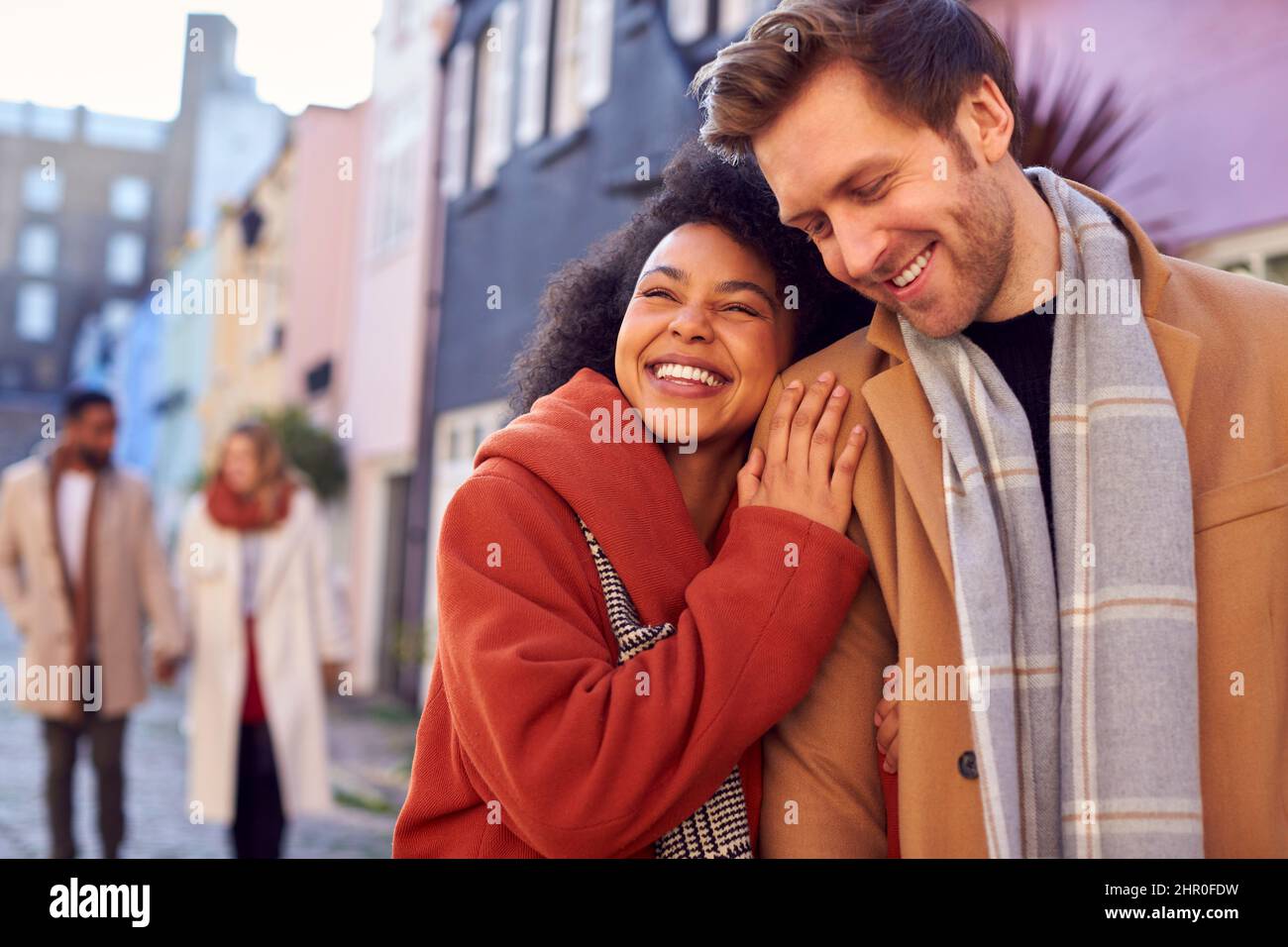 Multi Cultural Couple With Friends Walking Along Residential City ...