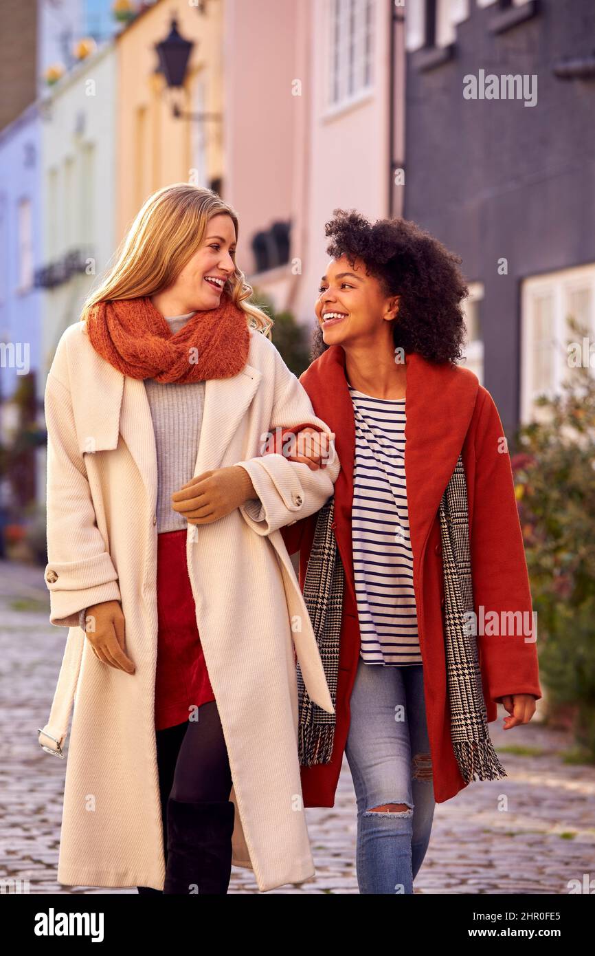 Woman Meeting Female Friend Walking Along Residential City Street In ...