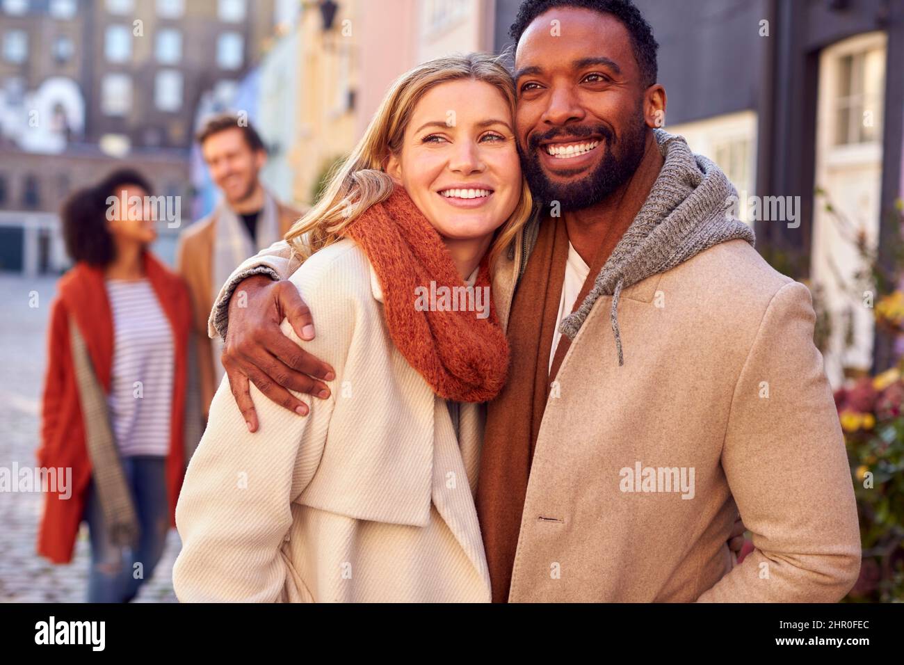 Multi Cultural Couple With Friends Walking Along Residential City ...