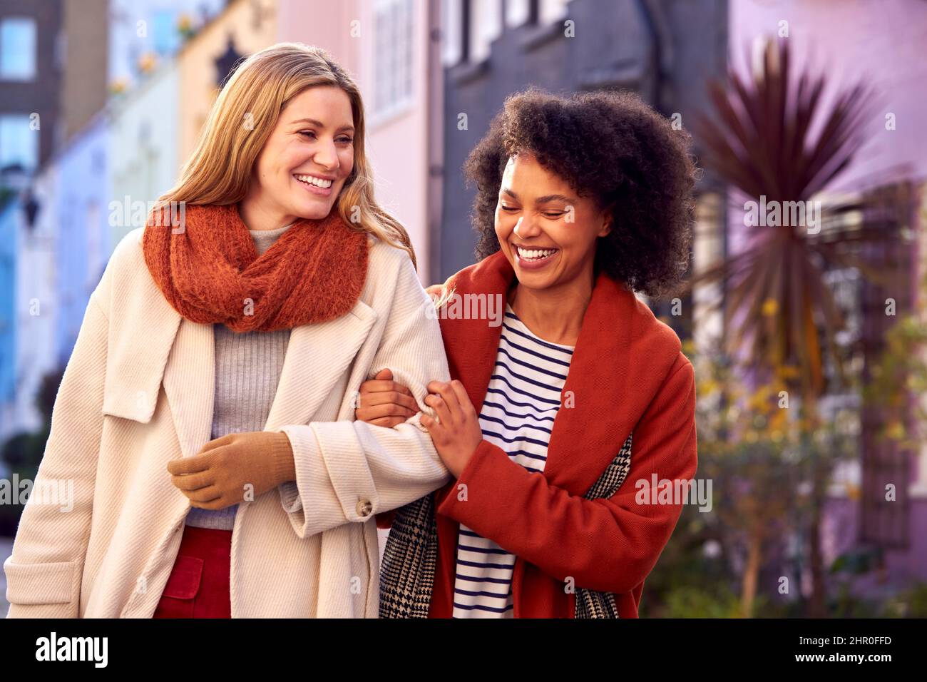Woman Meeting Female Friend Walking Along Residential City Street In ...