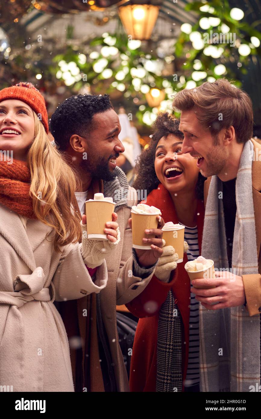 Group Of Friends Drinking Hot Chocolate With Marshmallows In Snow At ...