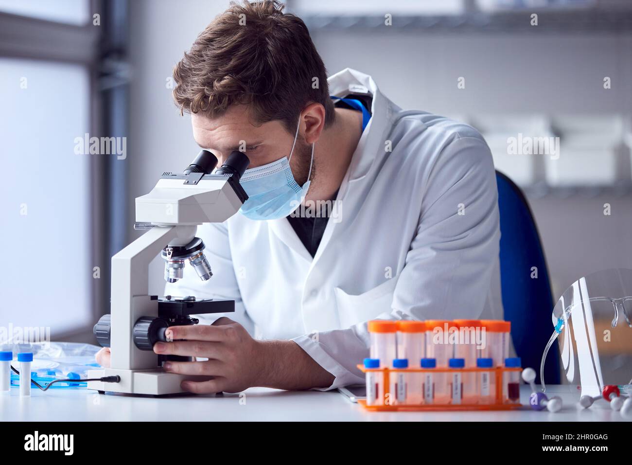 Male Lab Worker Wearing PPE Analysing Blood Samples In Laboratory With ...