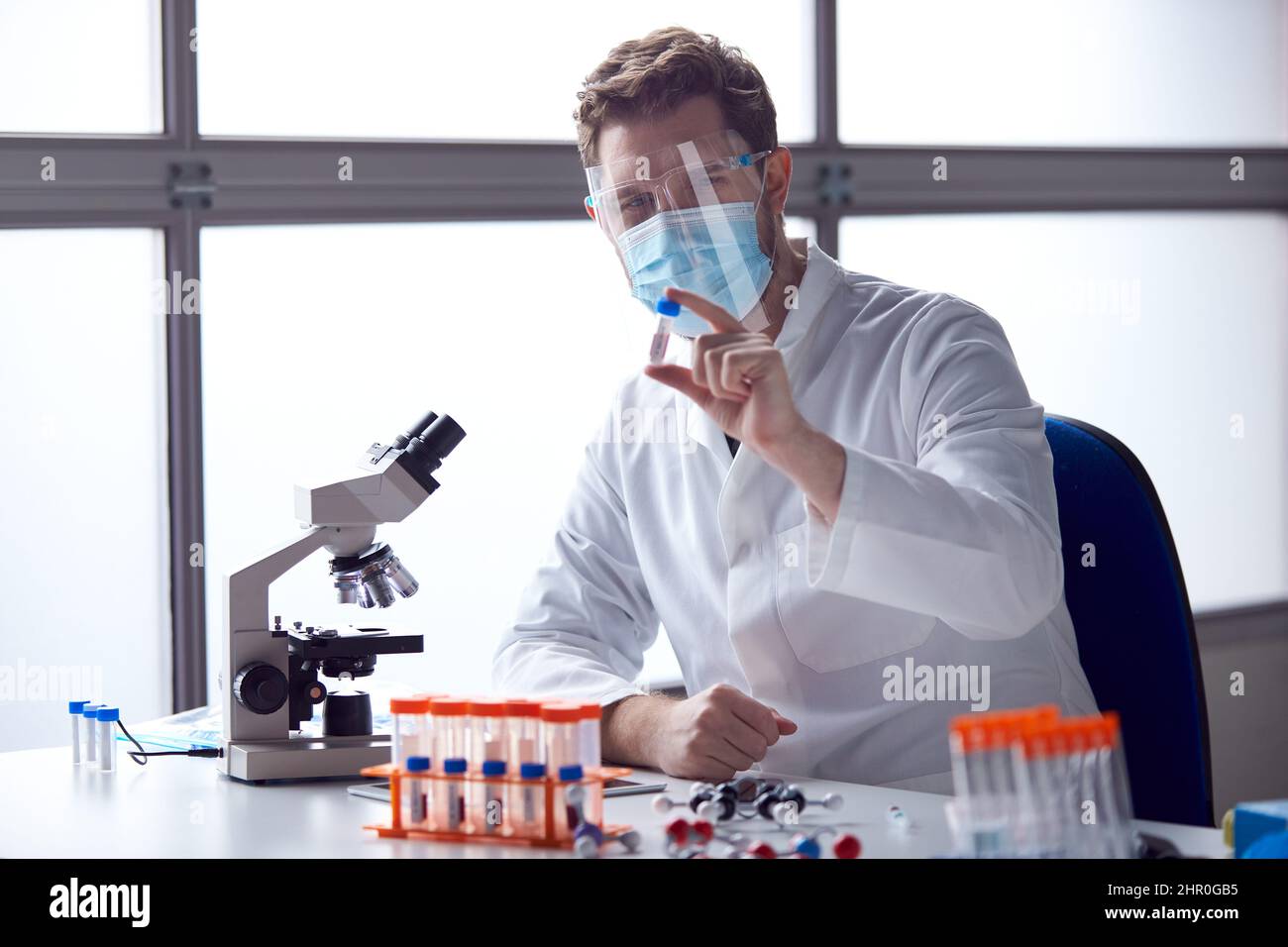 Male Lab Worker Wearing PPE Analysing Blood Samples In Laboratory With ...
