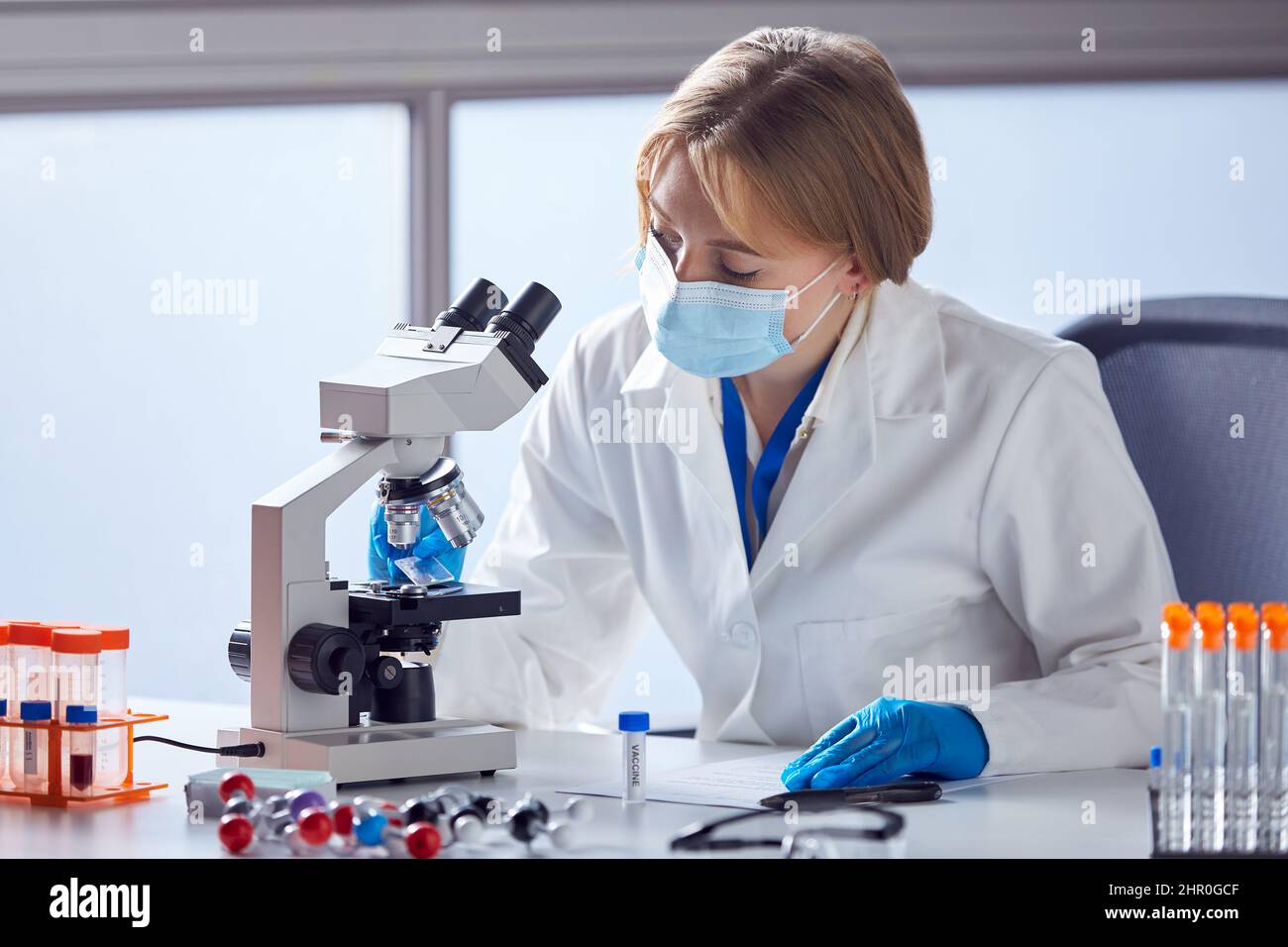 Female Lab Worker Wearing PPE Analysing Blood Samples In Laboratory ...