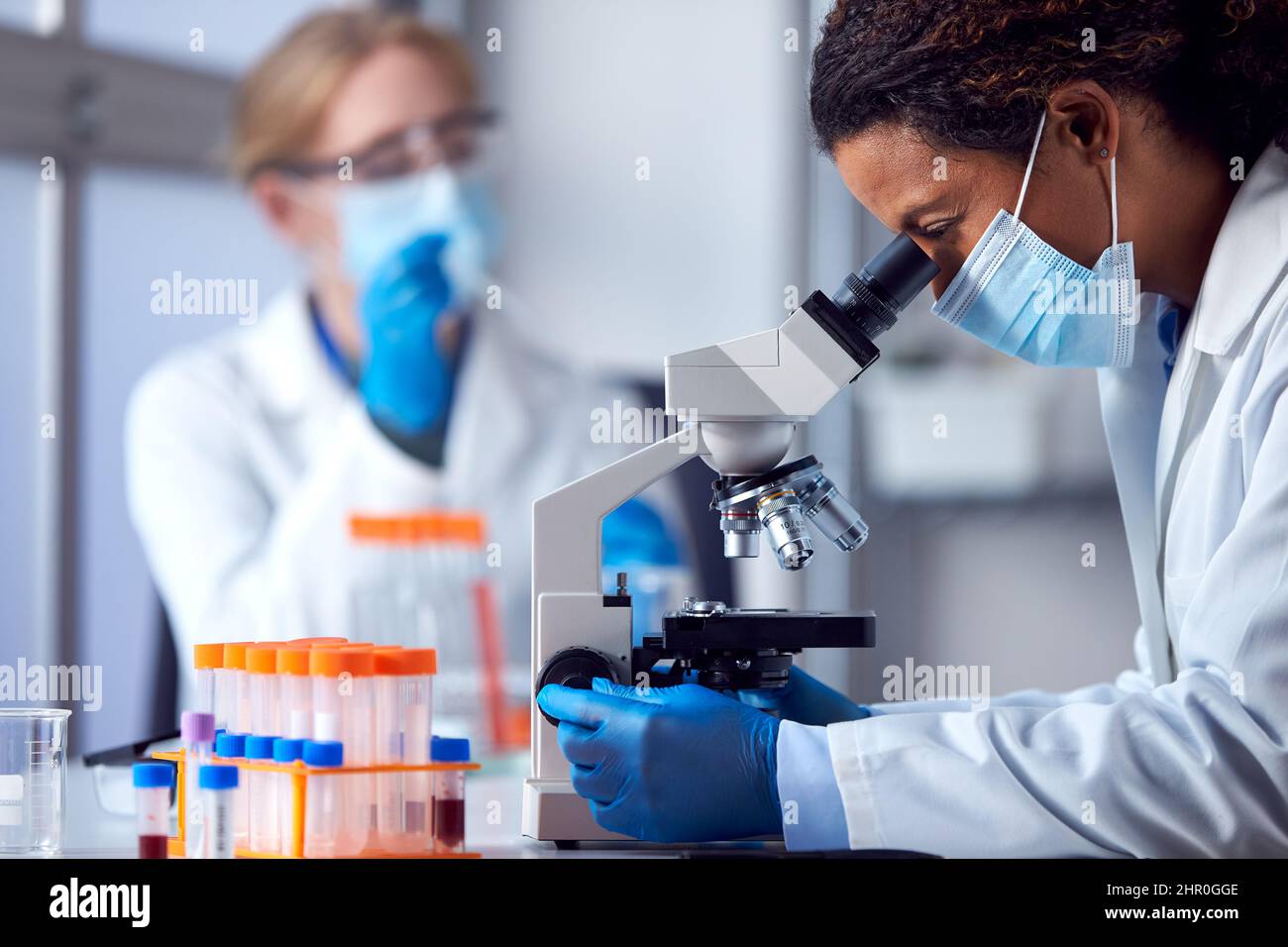 Two Female Lab Workers Wearing PPE And Safety Glasses Looking At Slide ...