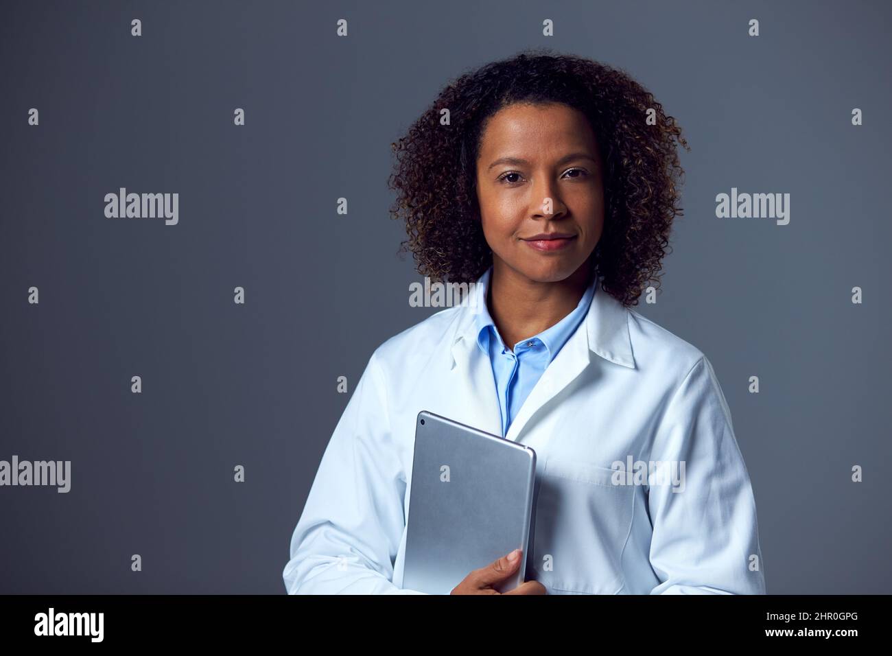 Studio Portrait Of Female Doctor In Lab Coat Holding Digital Tablet ...