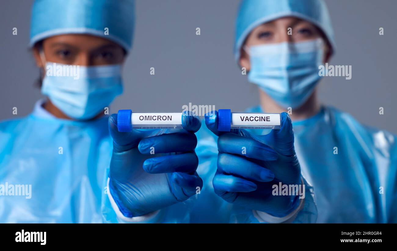 Two Female Lab Research Workers In PPE Holding Test Tubes Labelled ...