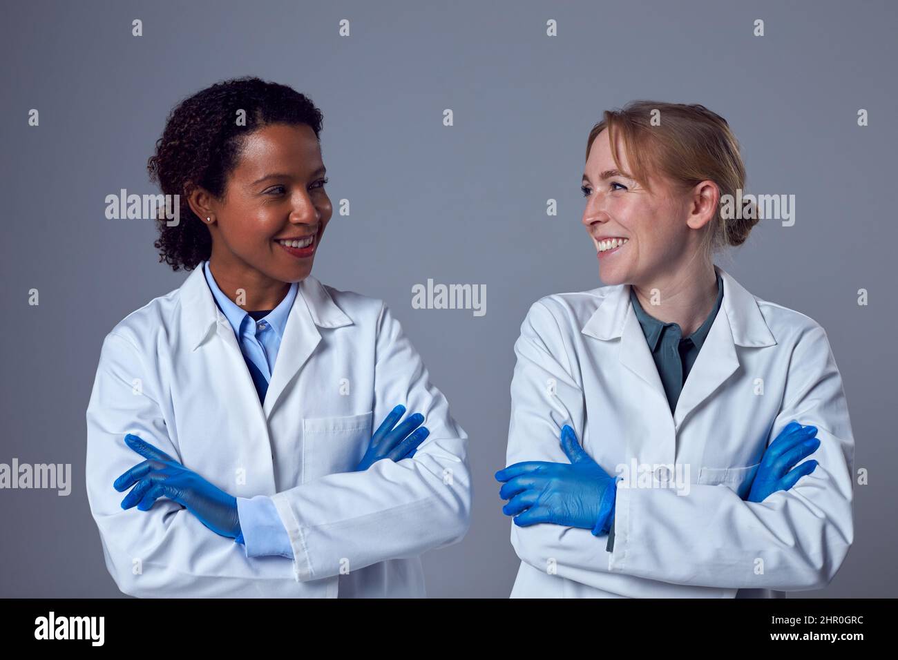 Studio Portrait Of Two Smiling Female Doctors Or Lab Workers In White ...