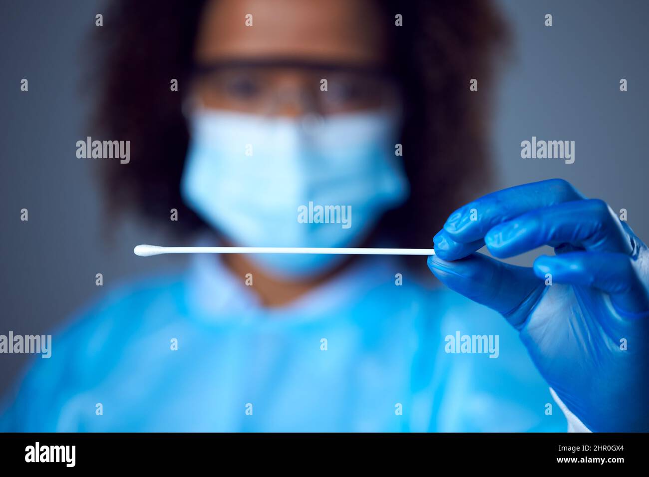 Female Lab Worker In PPE With Safety Glasses And Face Mask Holds Swab ...
