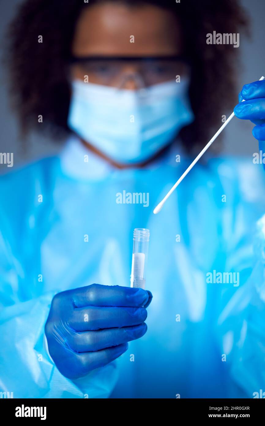 Female Lab Worker In PPE With Safety Glasses And Face Mask Holds Swab ...