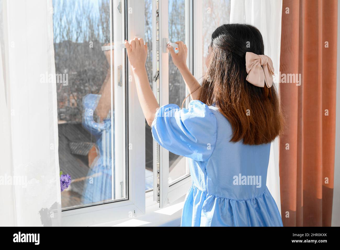 Pretty young Asian woman opening window in room Stock Photo - Alamy
