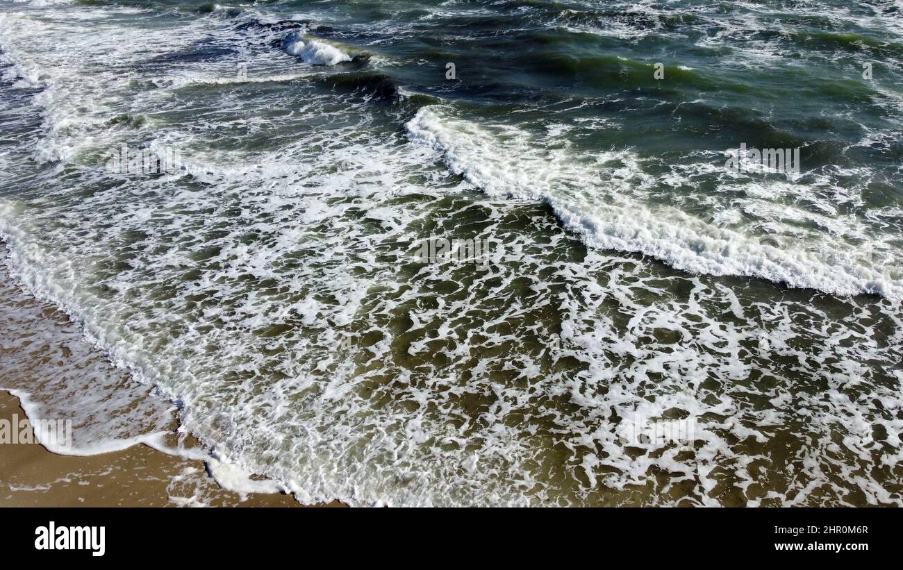 Aerial drone view flight over sea waves that roll onto sandy shore ...