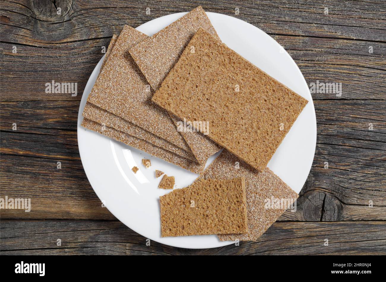 Crispy rye bread whole and broken in plate on old wooden table close up ...