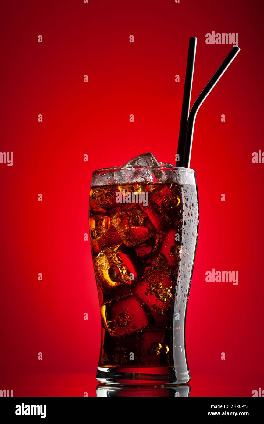 Cola with ice. Fresh cold sweet drink with ice cubes. Over red ...