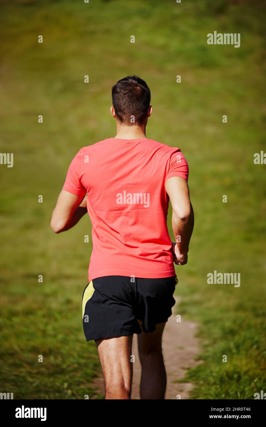 He wont stop now. High angle rearview shot of a young man running on an ...