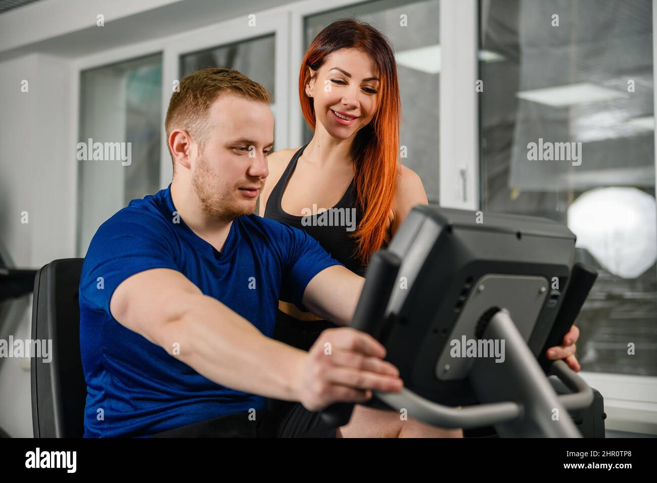 Trainer teach woman to use equipment machines at modern gym, look at ...