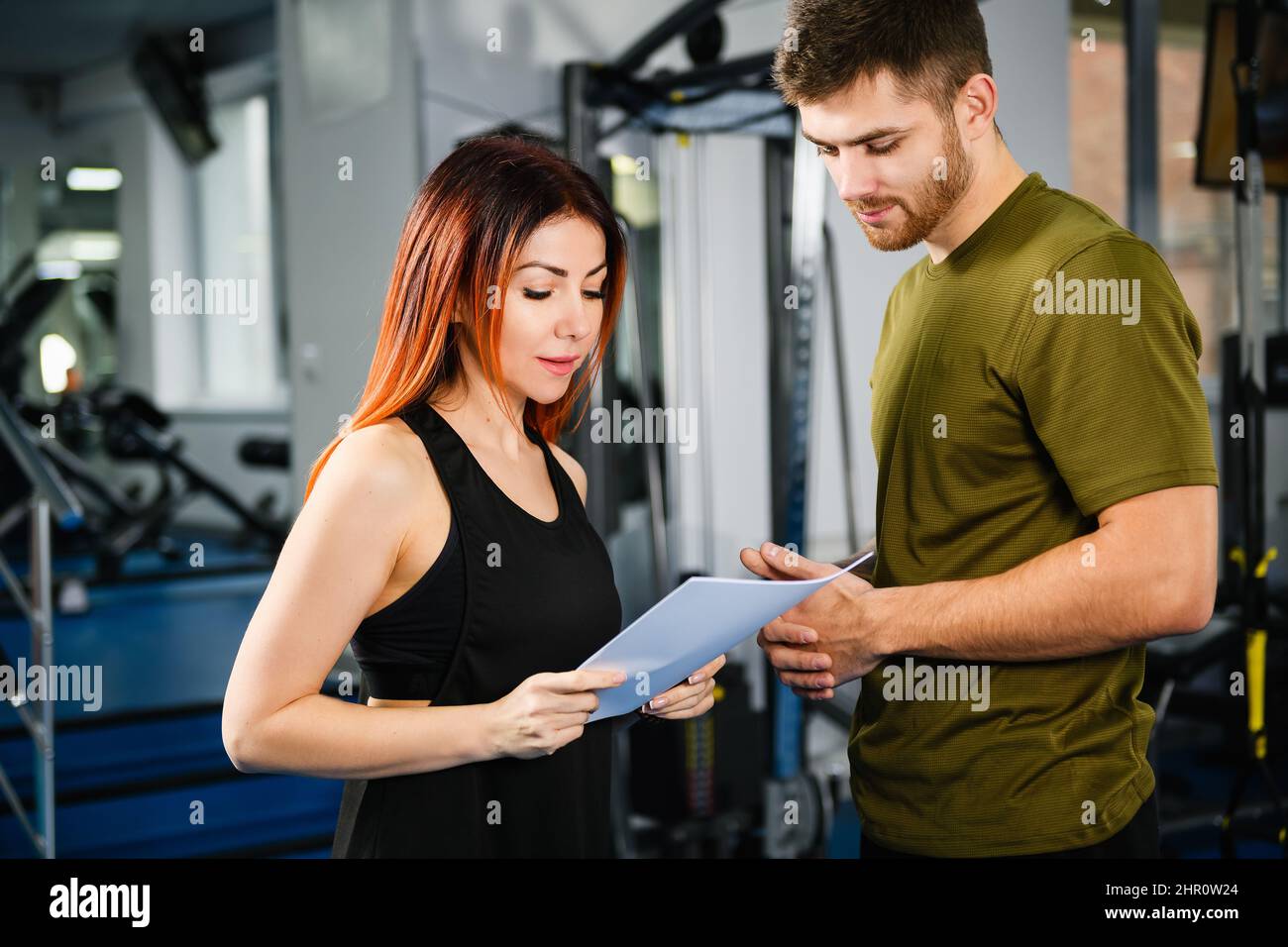 Fit woman customer client reading paper gym documents, instructions and ...