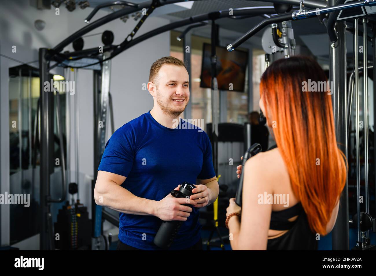 Woman customer talking with sport trainer coach at modern gym hall ...