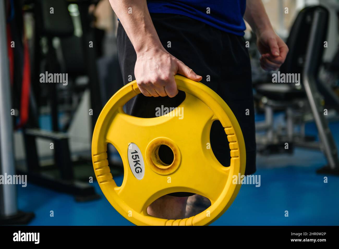 Strong muscular man hands with lifting yellow round heavy weight disk ...