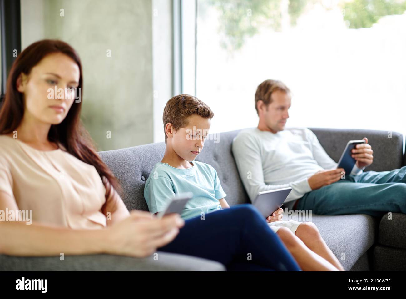 Left to their own devices.... Shot of a family of three sitting ...