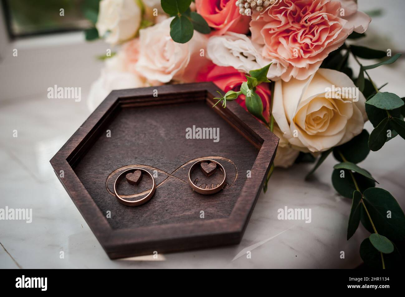 Beautiful bridal bouquet, a pair of golden wedding rings in a wooden ...