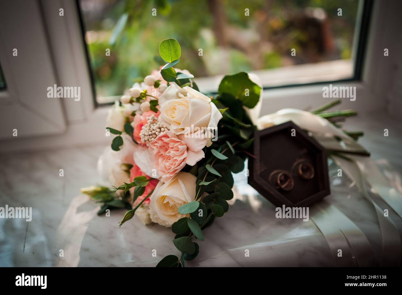 Beautiful bridal bouquet, a pair of golden wedding rings in a wooden ...