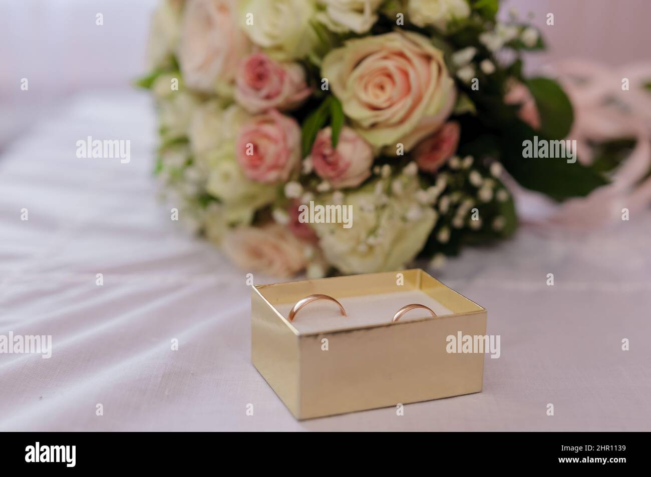 Beautiful bridal bouquet, a pair of golden wedding rings in a wooden ...