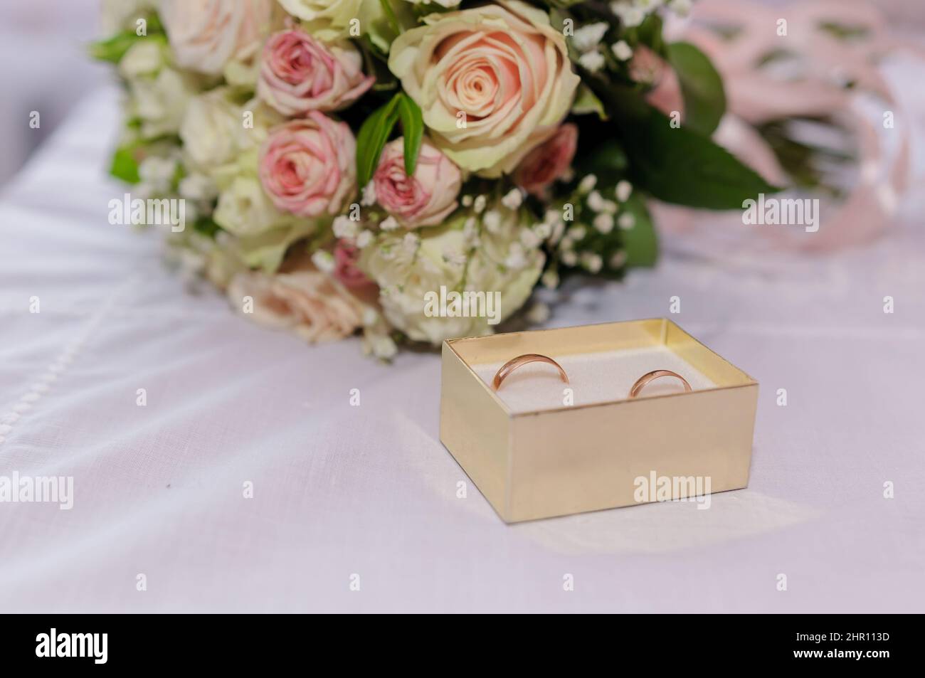 Beautiful bridal bouquet, a pair of golden wedding rings in a wooden ...