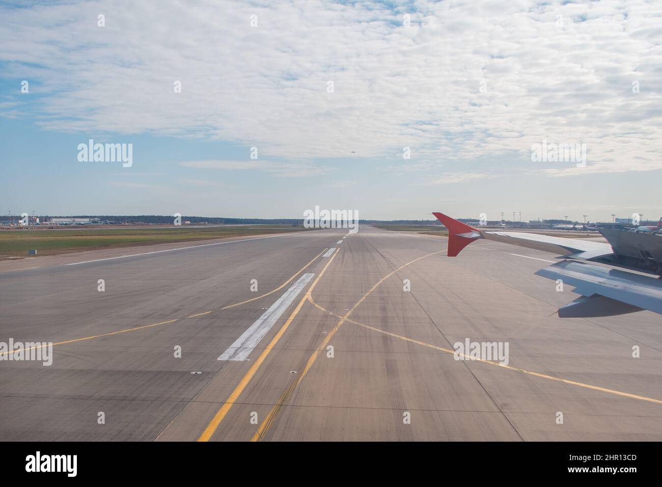 Wing view runway at the airport sky and a airplane taking off in the ...