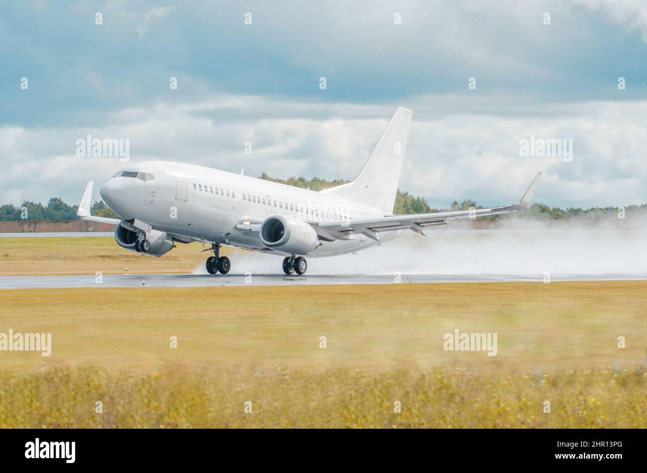 Airplane lit by the sun takes off in a wet runway during the rain at ...