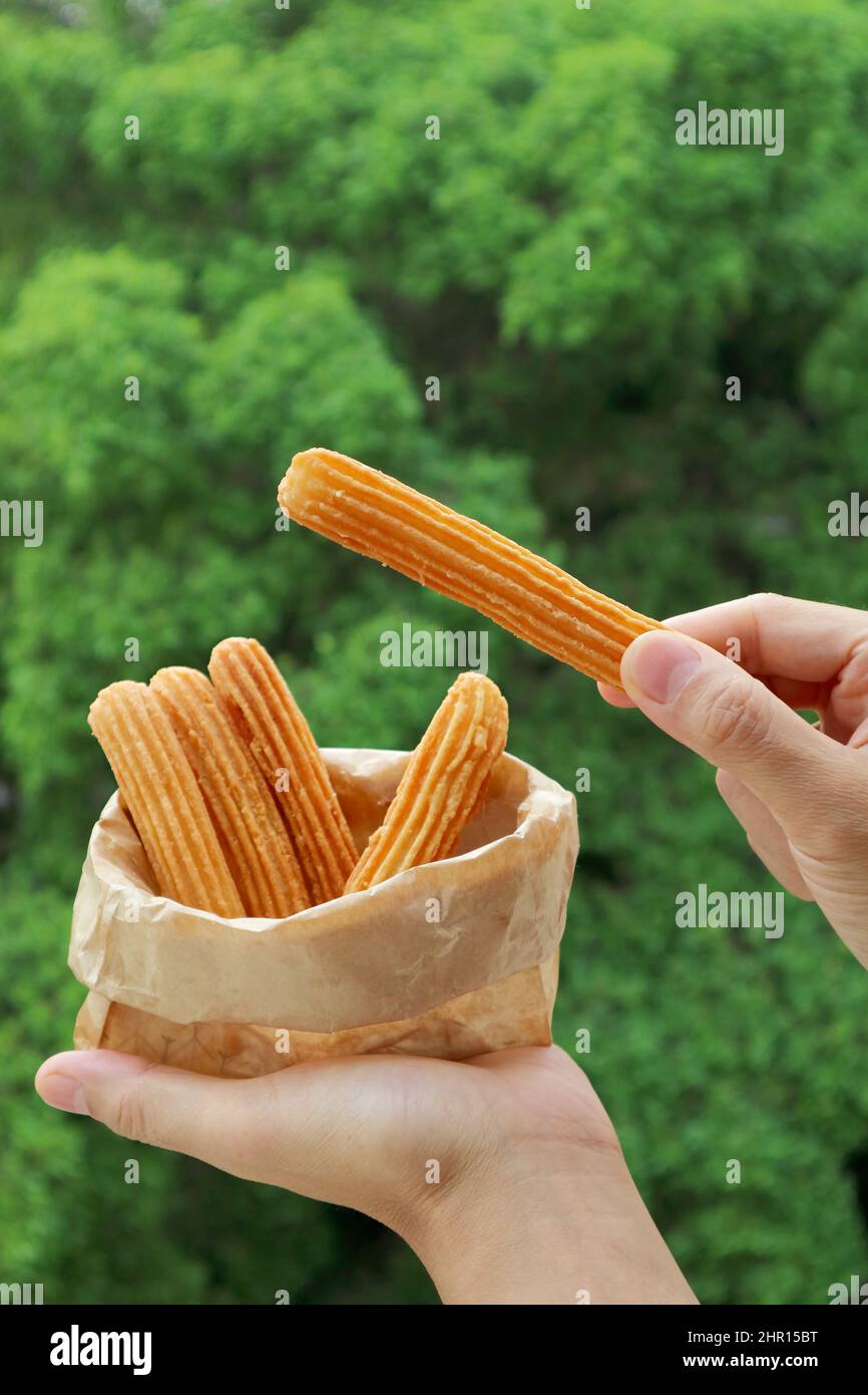 Hand Picking a Stick of Fresh Fried Churro from Paper Bag Stock Photo ...