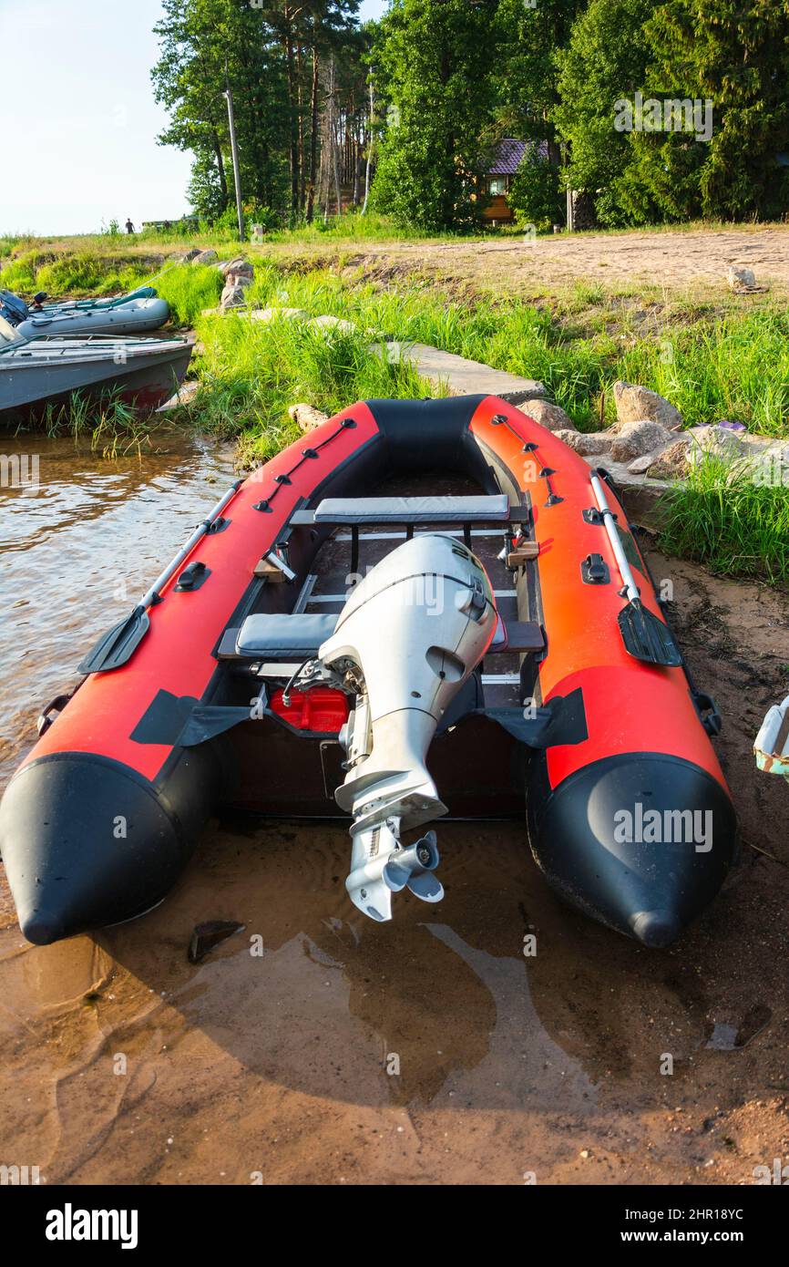 Red inflatable rubber boat with a motor near the lake shore, fishing ...