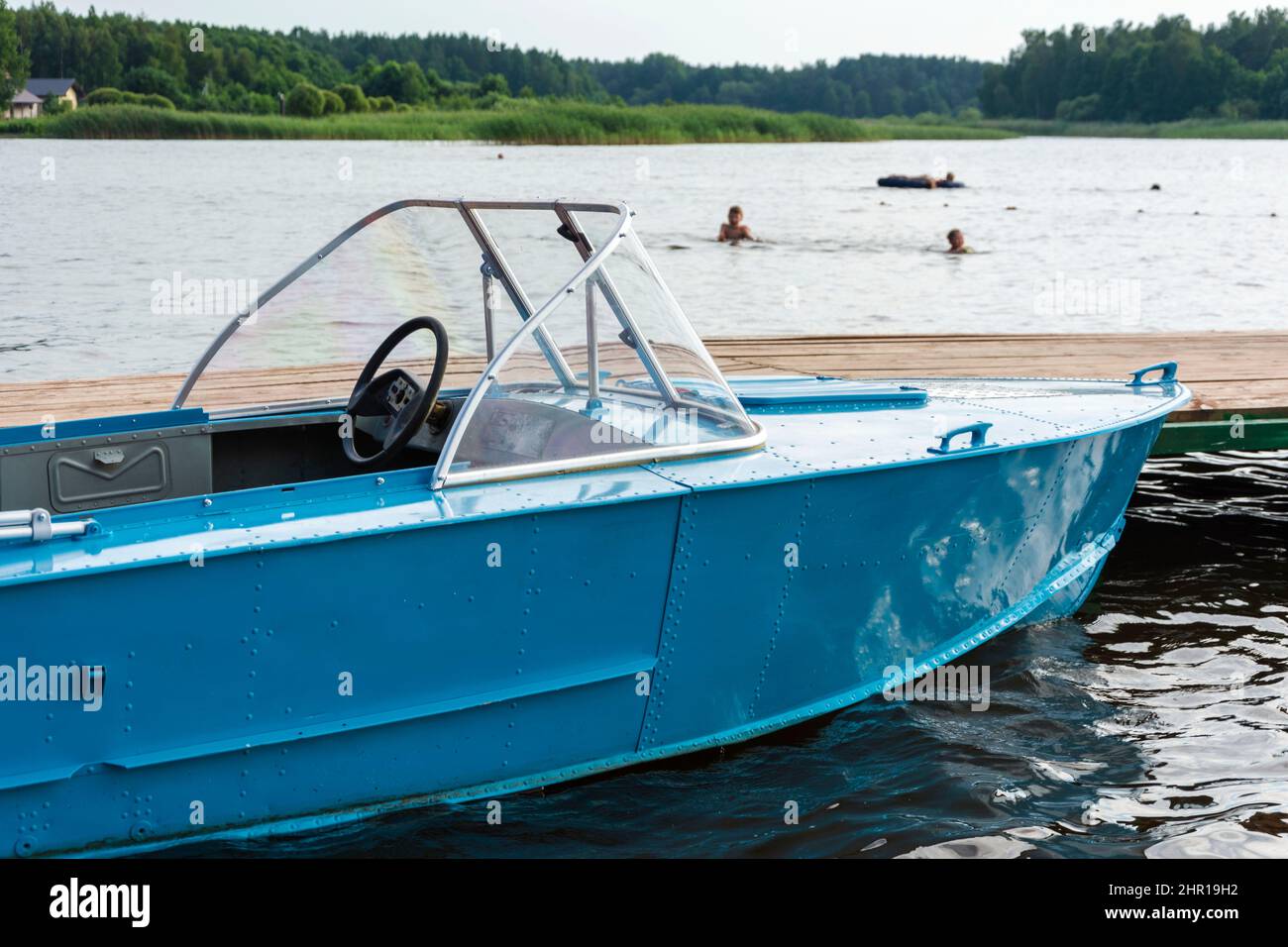 Aluminum blue fishing boat with a motor near the lake shore, fishing ...