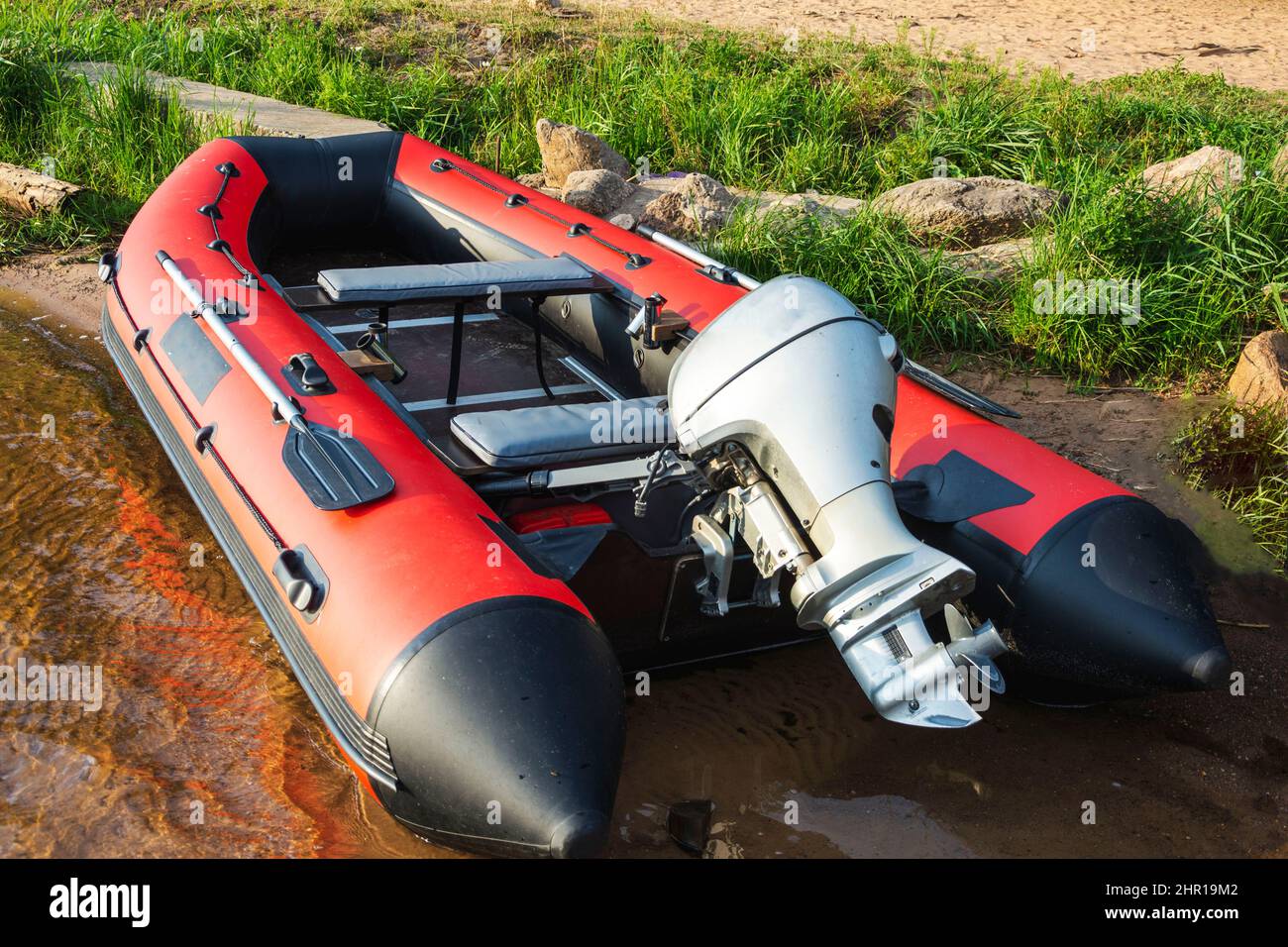 Red inflatable rubber boat with a motor near the lake shore, fishing ...