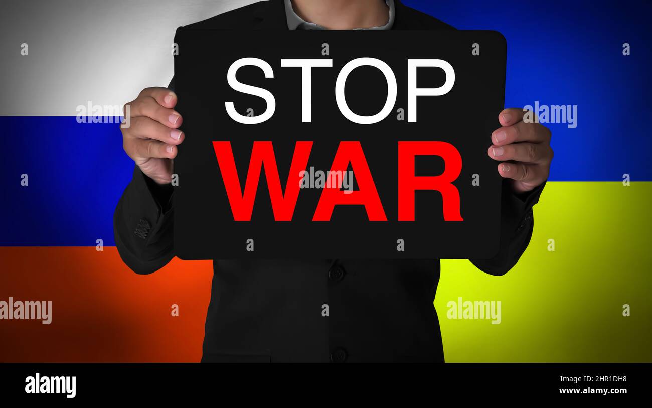 Young Man Holding Stop War Cardboard in front of Two Flags. Say no to ...