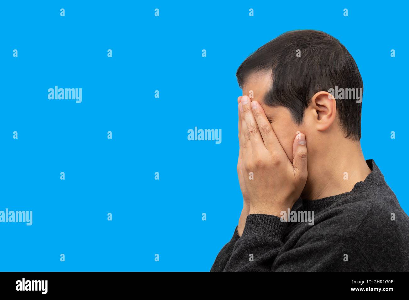 Close-up view of a man covering his face and crying with blue ...