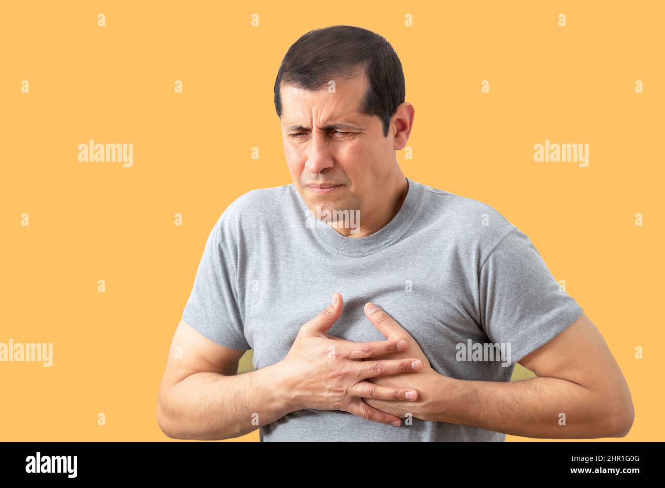 Shot of a man holding his chest in discomfort due to pain with yellow ...