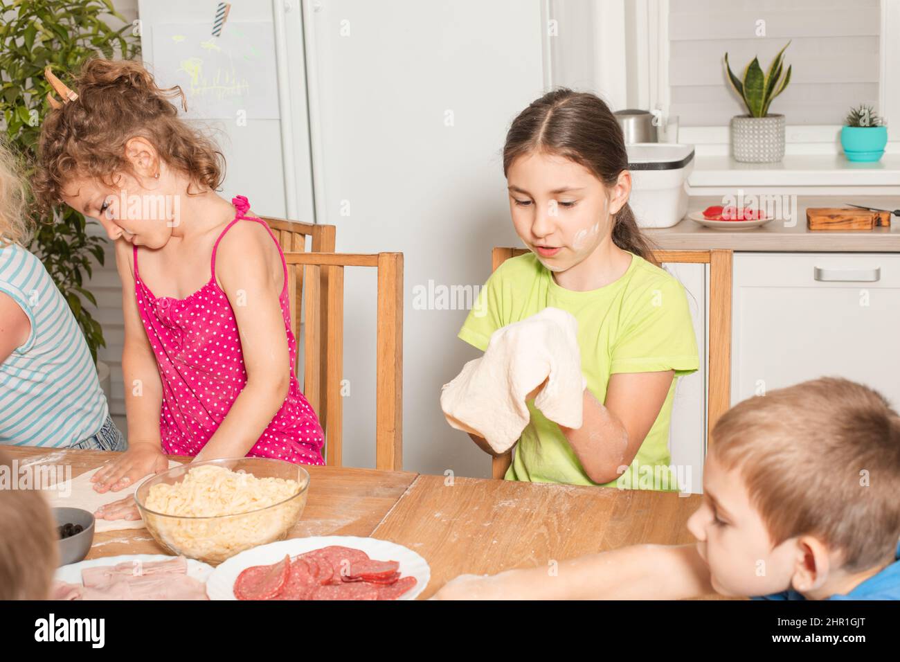 Happy kids sit at a table in the kitchen and make pizza Stock Photo - Alamy