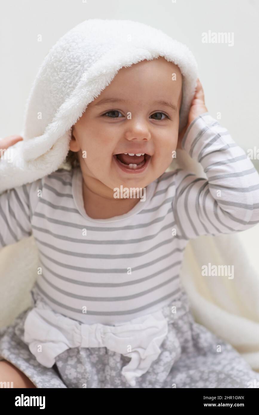 Peek-a-boo. Shot of a cute little baby girl sitting on the floor ...