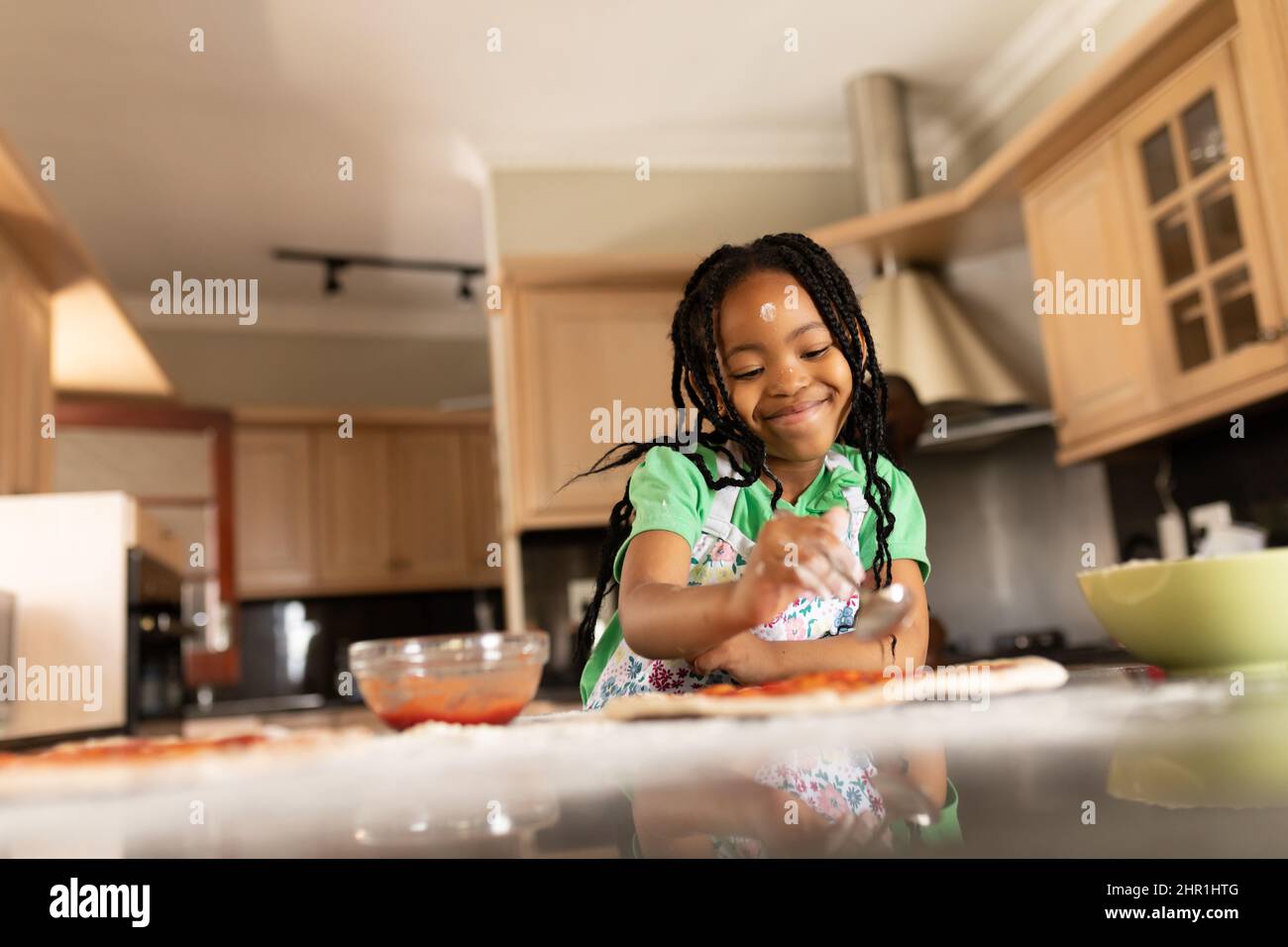 Smiling cute african american girl with black braids making pizza at ...