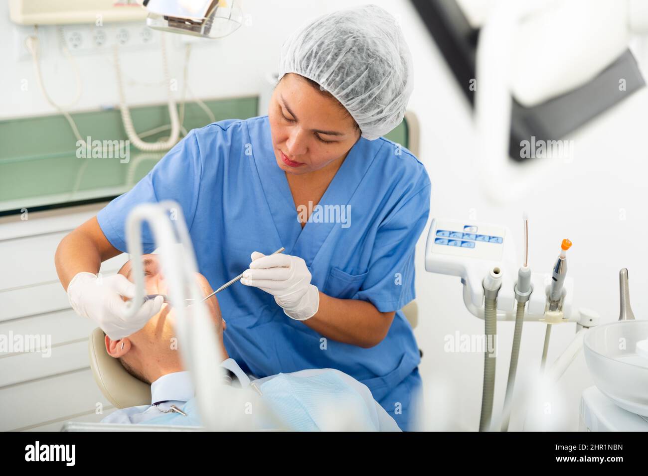 Dentist professional filling teeth for man patient sitting in chair ...