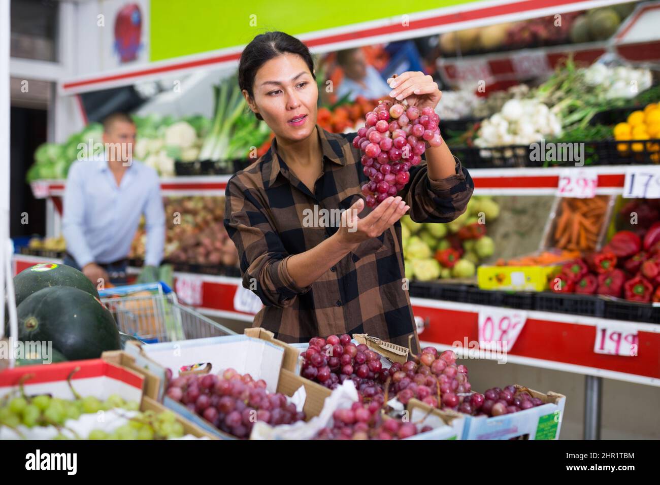 Female buyer choosing grapes in fruit and vegetable department of ...