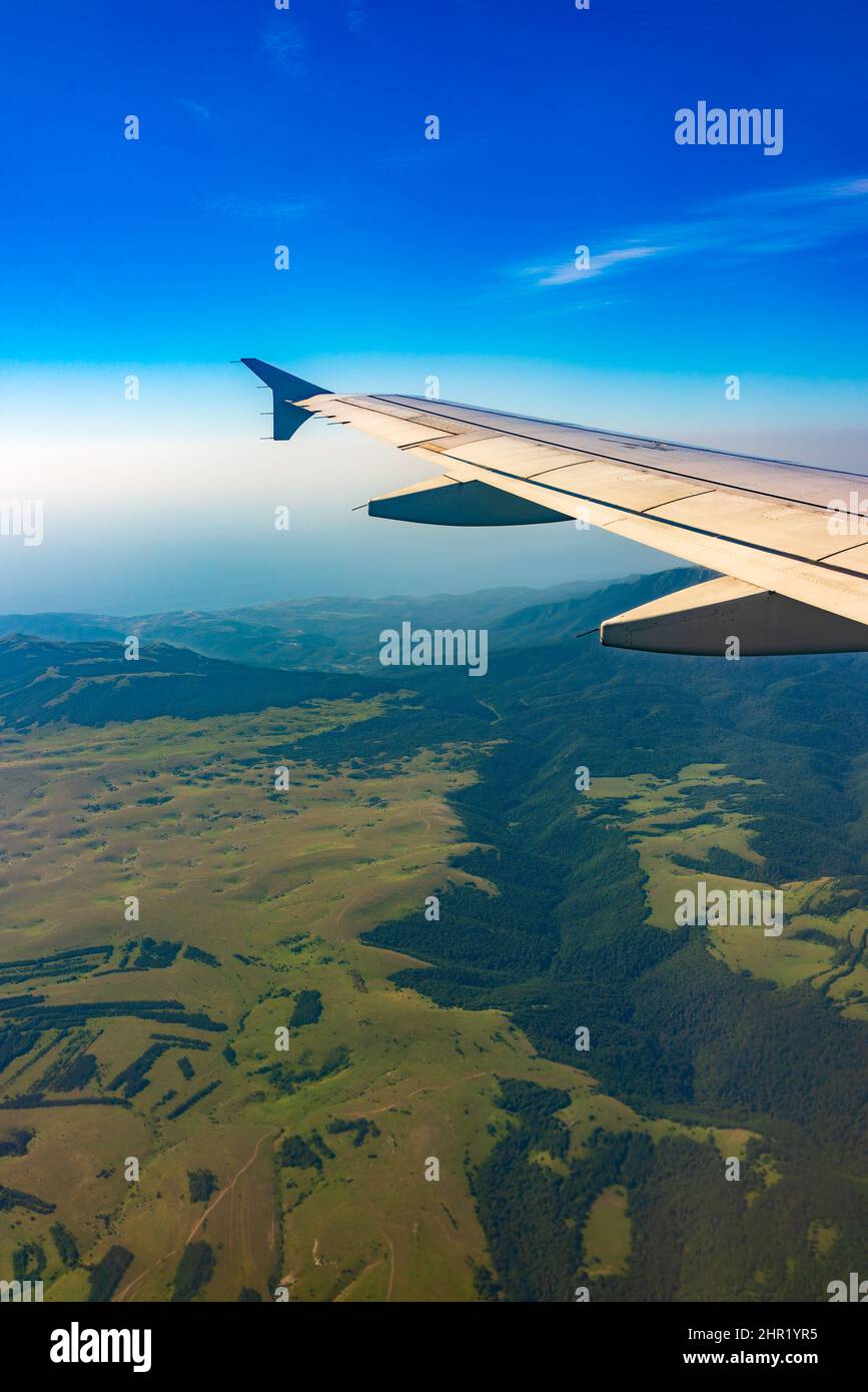 View of airplane wing, blue skies and green land during landing ...