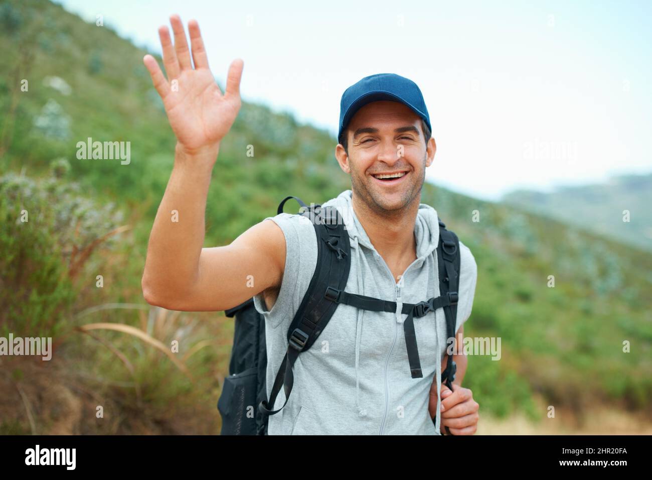 Waving goodbye to the city life. Happy young hiker waving at the camera ...