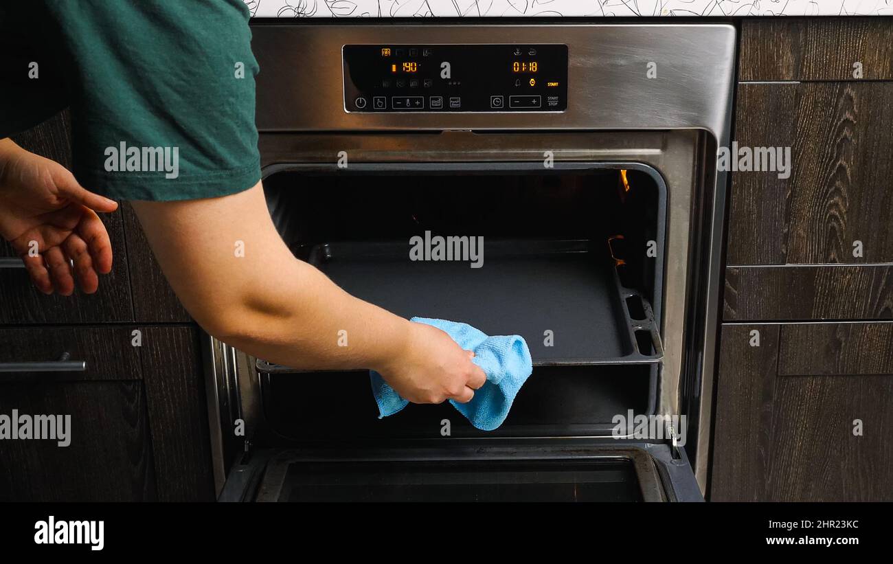 A woman's hand opens the oven door and pulls out a tray. Preparing to ...