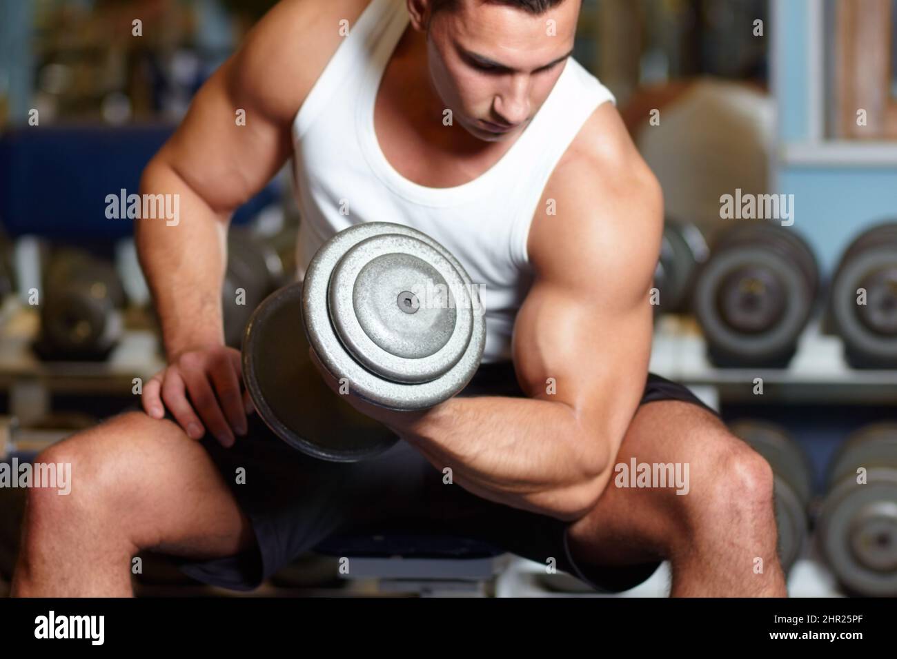 Building his biceps. A muscular young man working out in the gym Stock ...