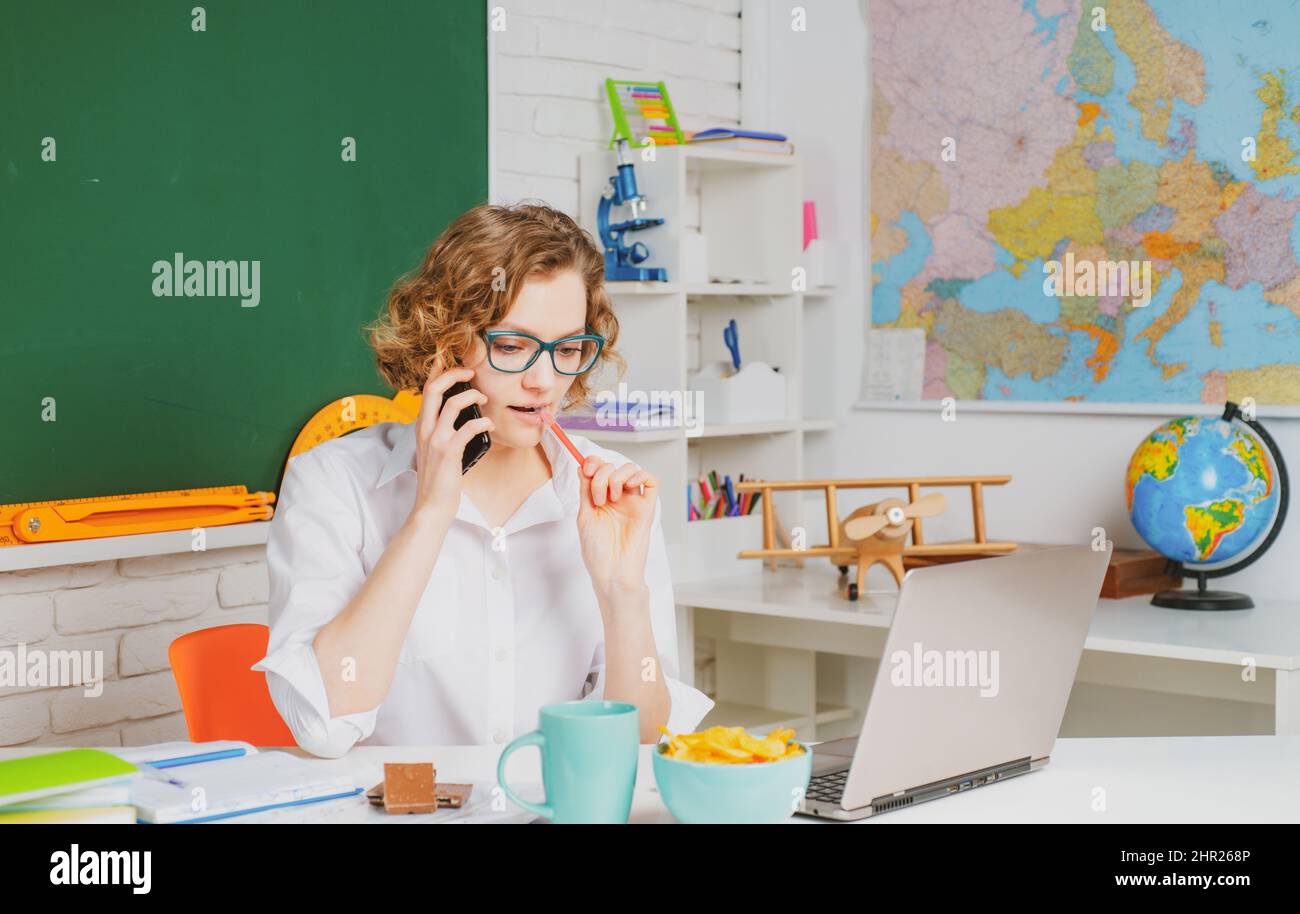 Portrait of confident female teacher with mobile phone near blackboard ...