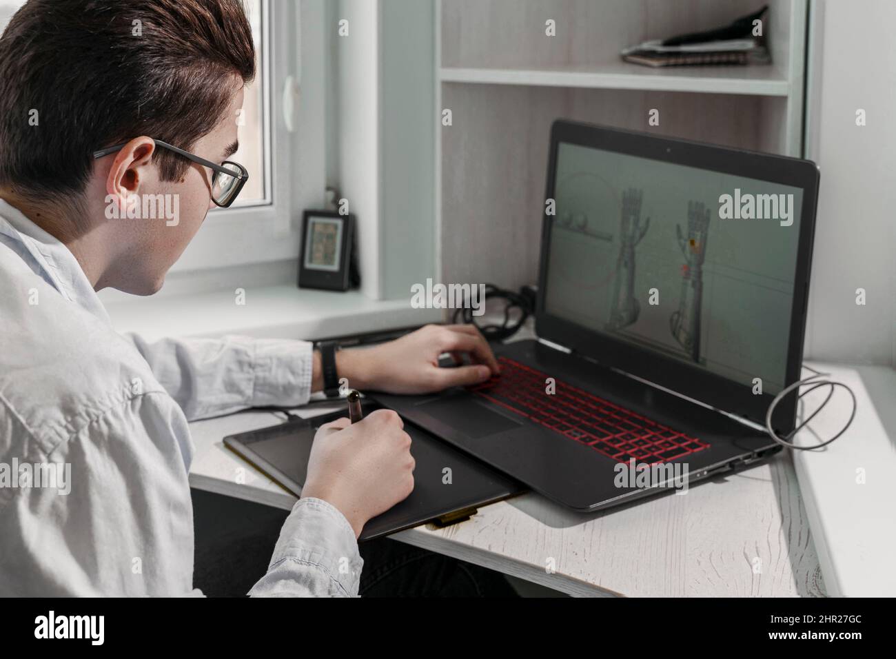 Young student male 3D designer uses graphics tablet to work at his desk ...