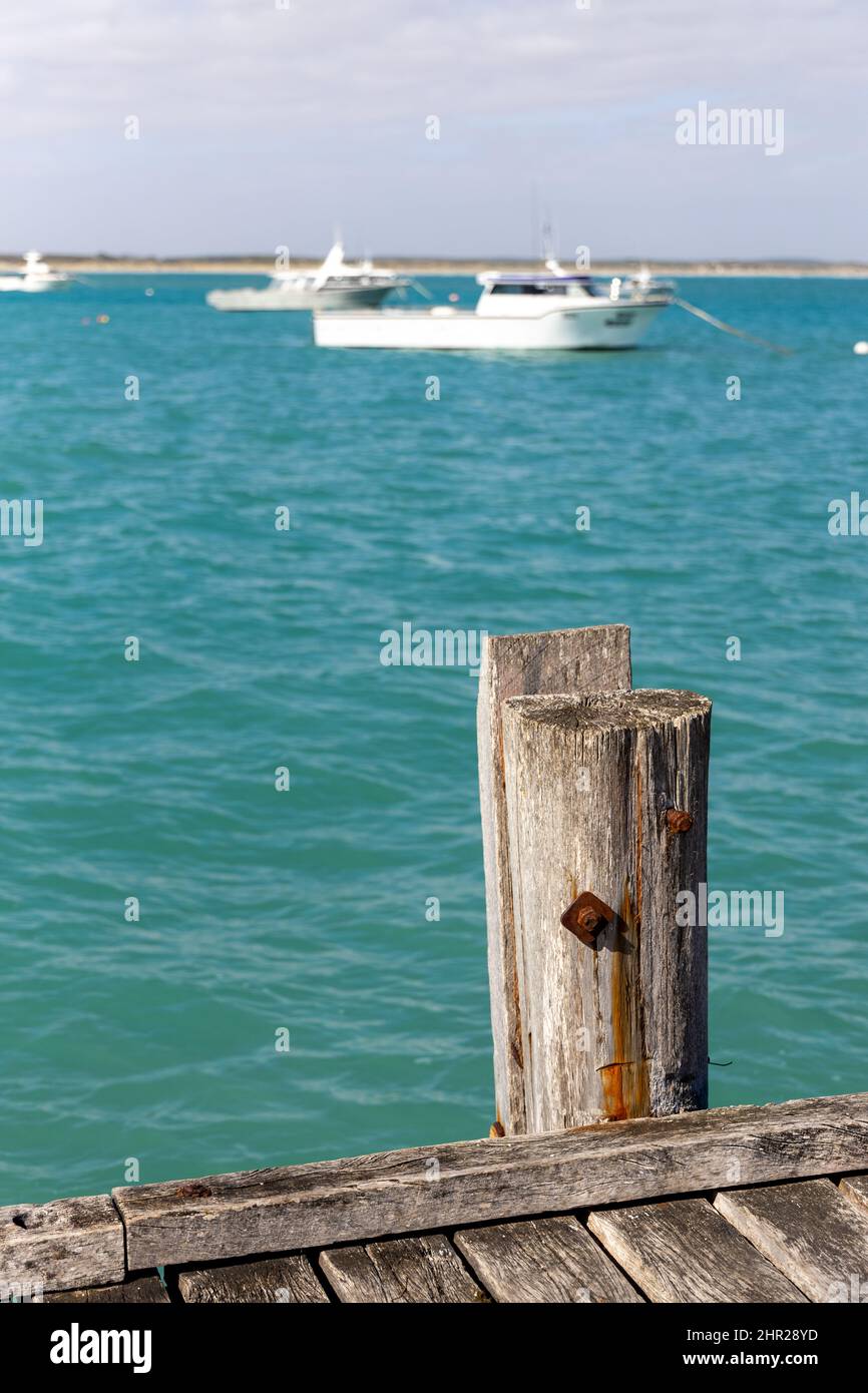 A jetty pylon with selectively blurred fishing boats located in ...