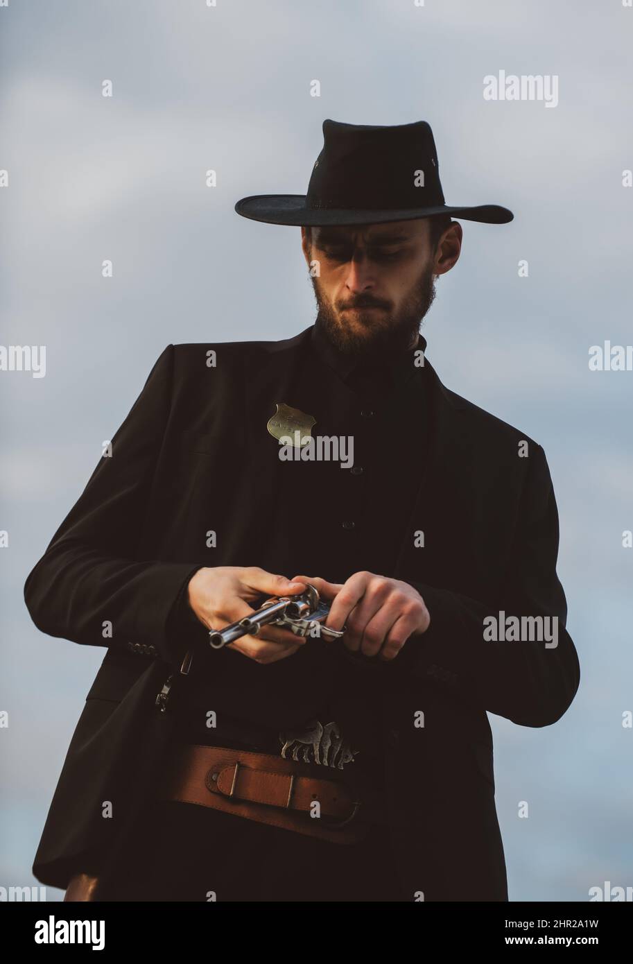 Cowboy shooter in black suit and cowboy hat. Serious man with wild west ...